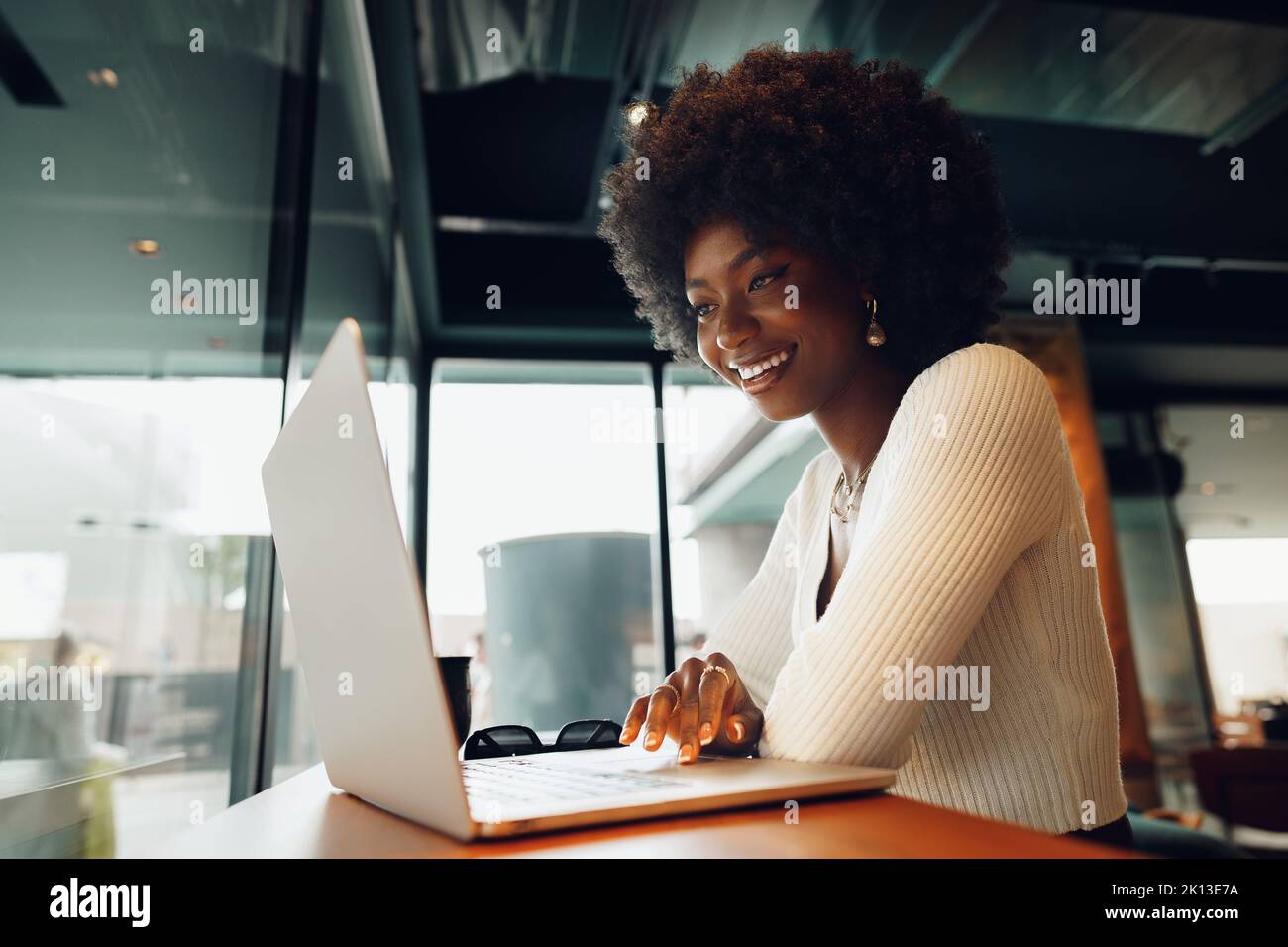 Smiling young african woman sitting with laptop in cafe Stock Photo - Alamy