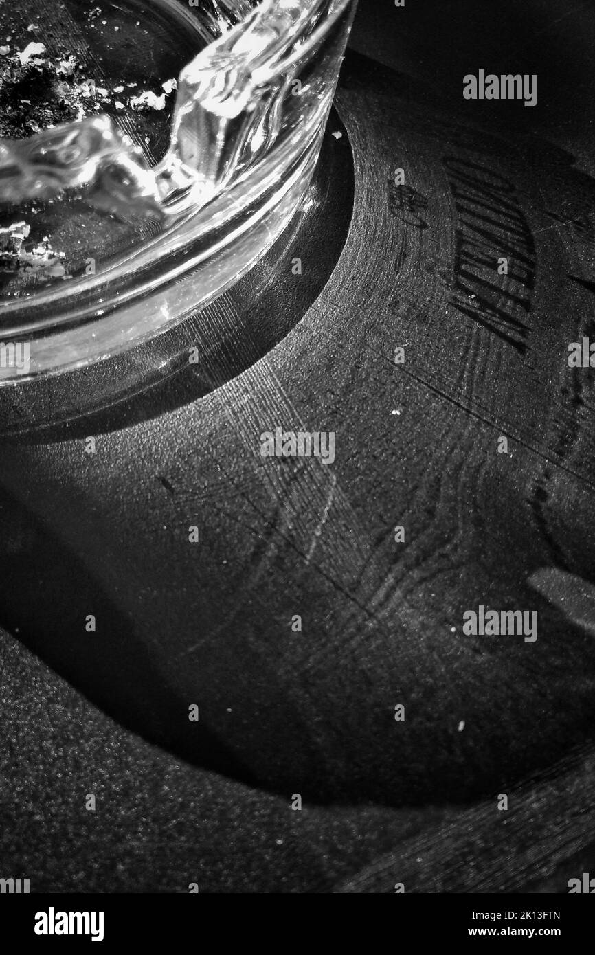 A vertical grayscale closeup shot of an ashtray with reflection on the ...