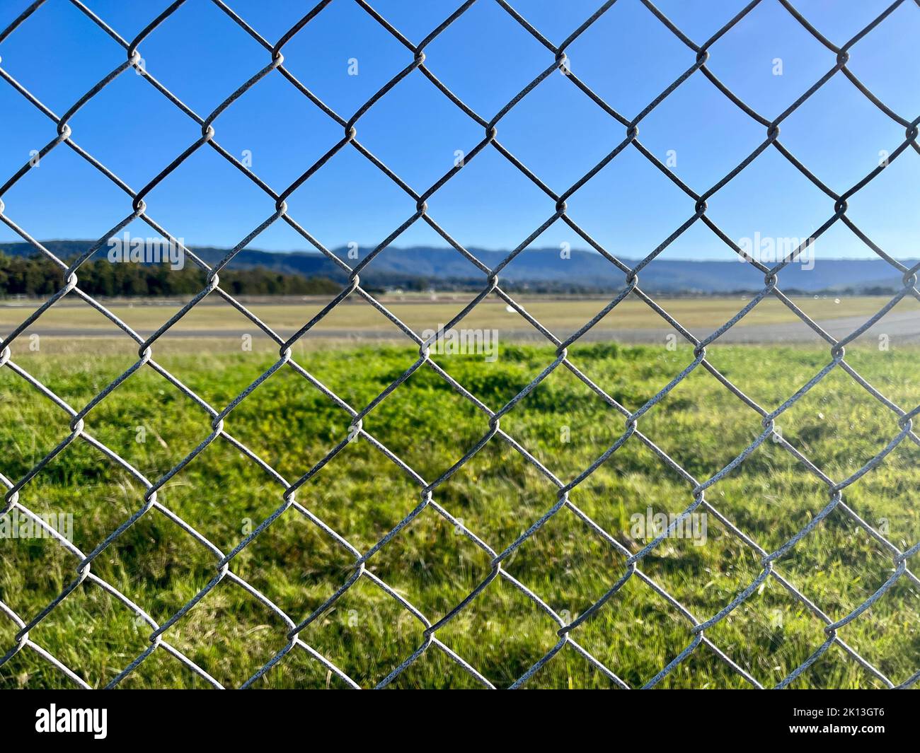 A green lawn land behinf a net wire fence Stock Photo - Alamy