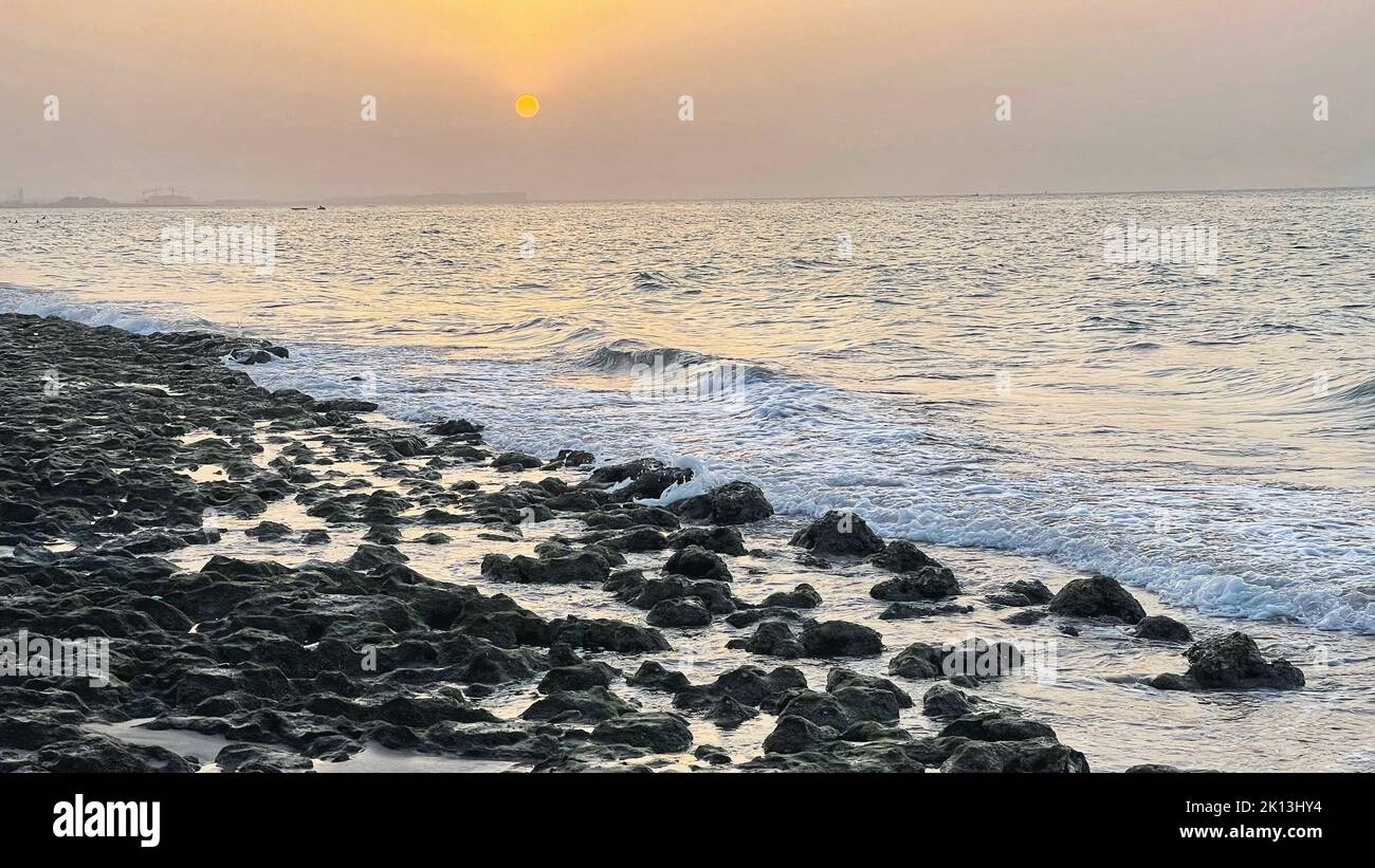 The ocean waves approaching a rocky beach with grey sand captured at ...