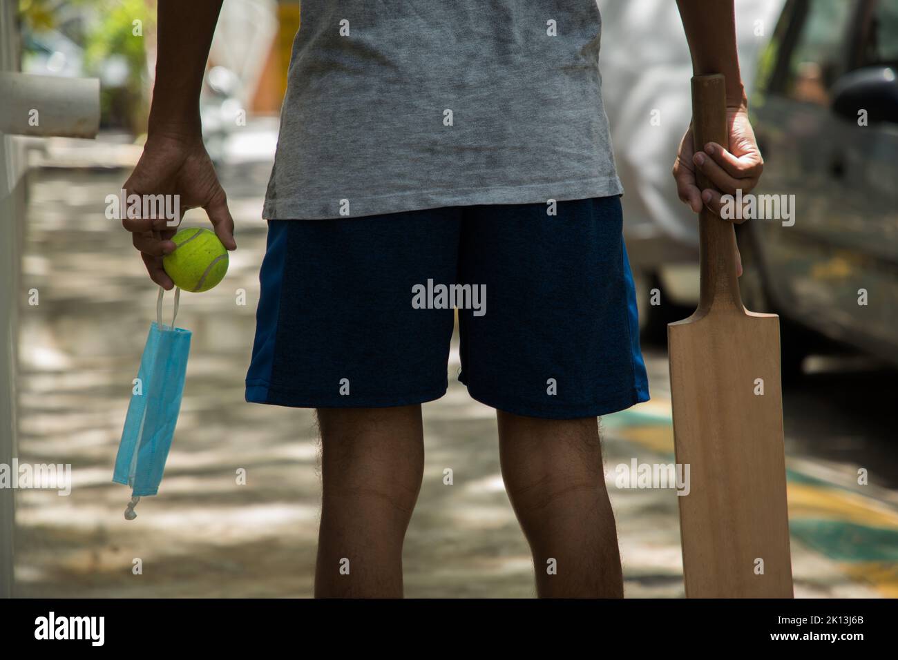 A closeup shot of person holding a cricket bat and a ball with a blur ...
