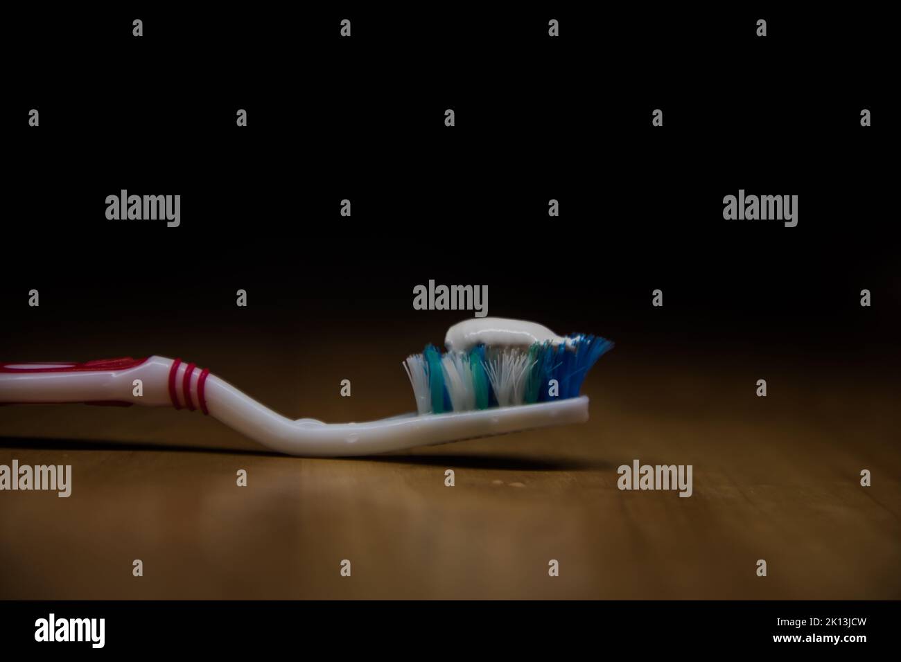 A closeup side view of toothbrush with toothpaste on it lying on a ...