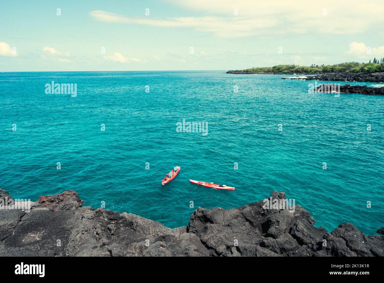 An aerial view of red kayaks on blue water near the shore of Big Island ...