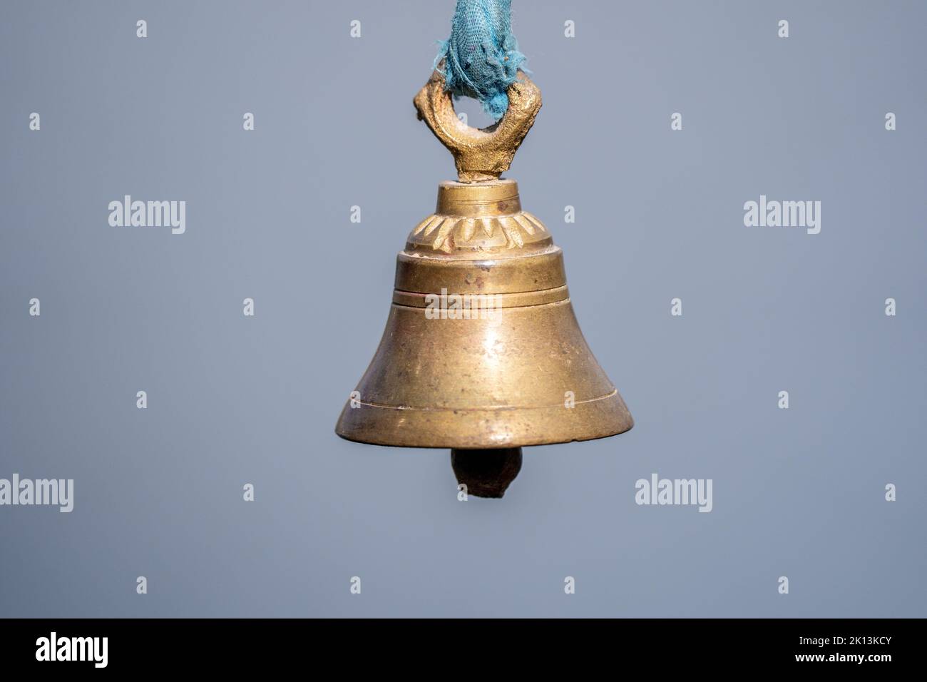 A closeup shot of gold plated brass temple bell isolated on a grey ...