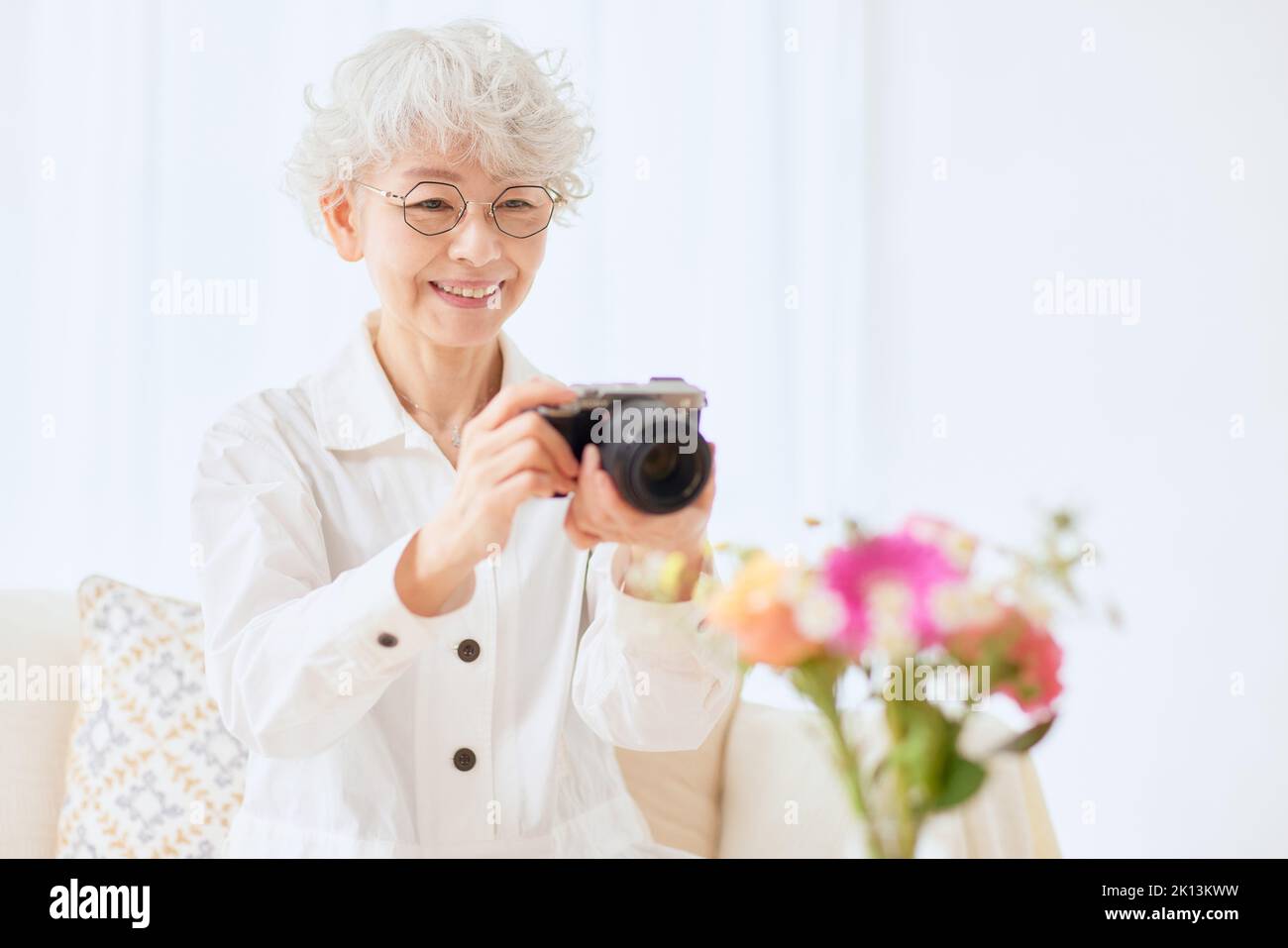 Japanese senior woman taking pictures of flowers on the sofa Stock ...