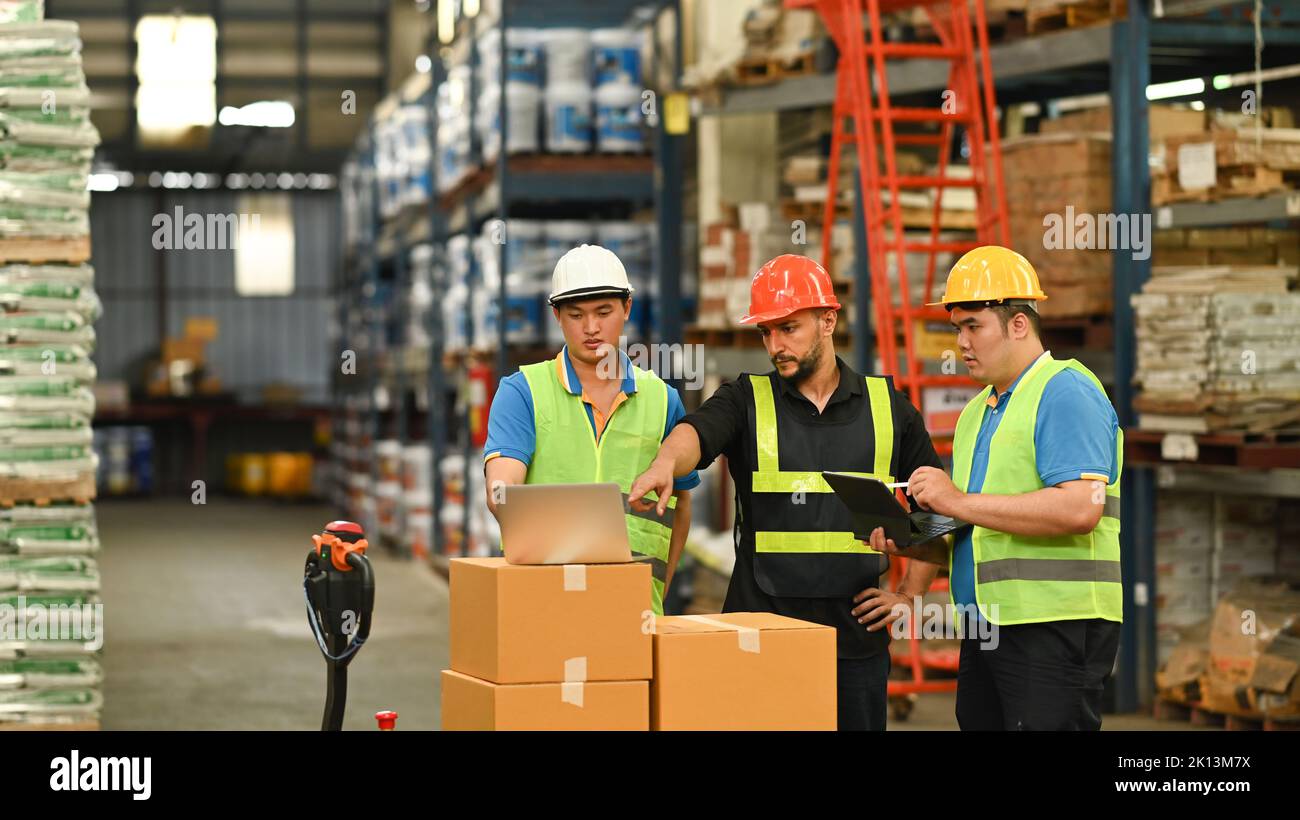 Manager and warehouse worker inspecting stock tick and cardboard stock ...