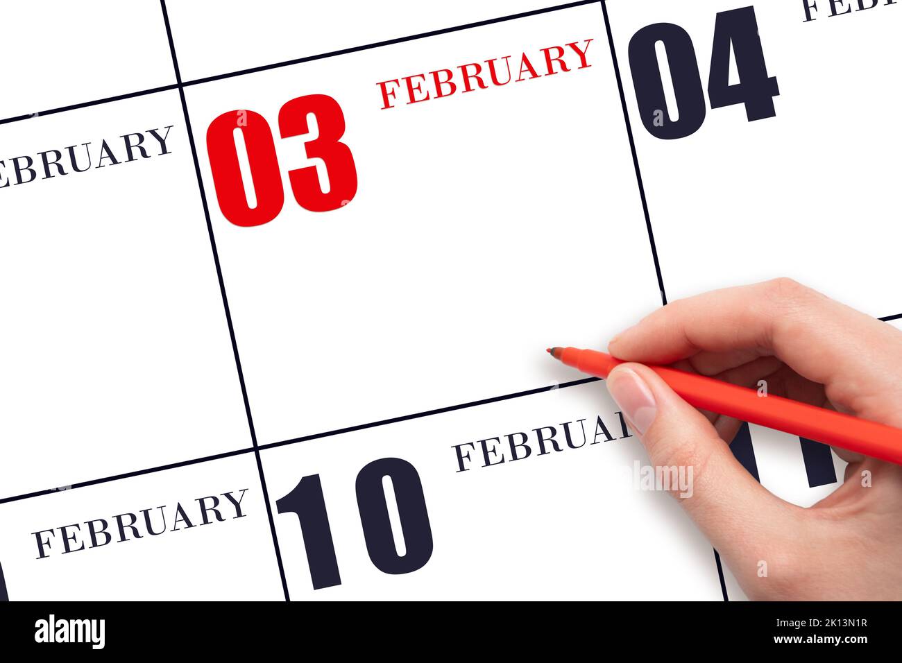 3rd day of February. A hand holding a red pen and pointing on the ...