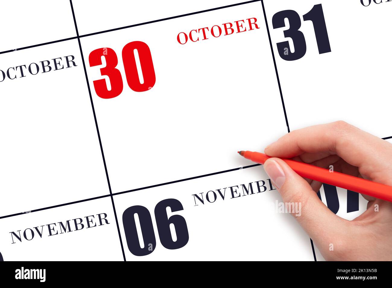 30th day of October. A hand holding a red pen and pointing on the ...