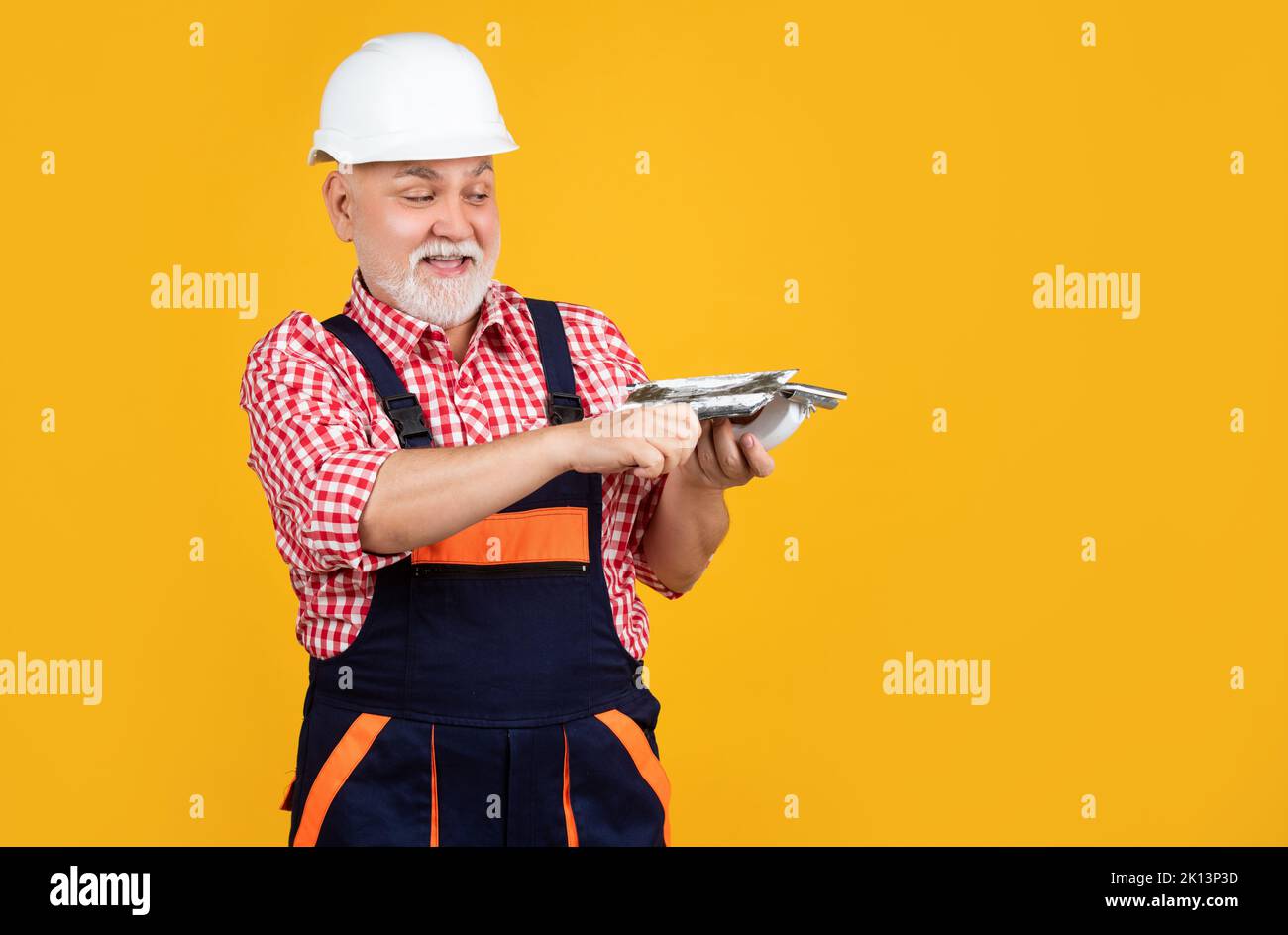 happy aged man plasterer in helmet on yellow background Stock Photo - Alamy