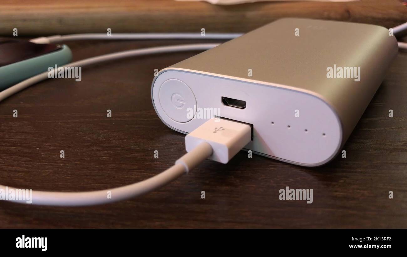 Silver powerbank external battery charging smartphone lying on the ...