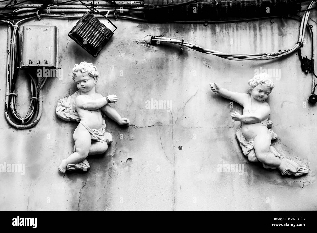 Decorative stone angels on wall surrounded by electric cables in Spain ...