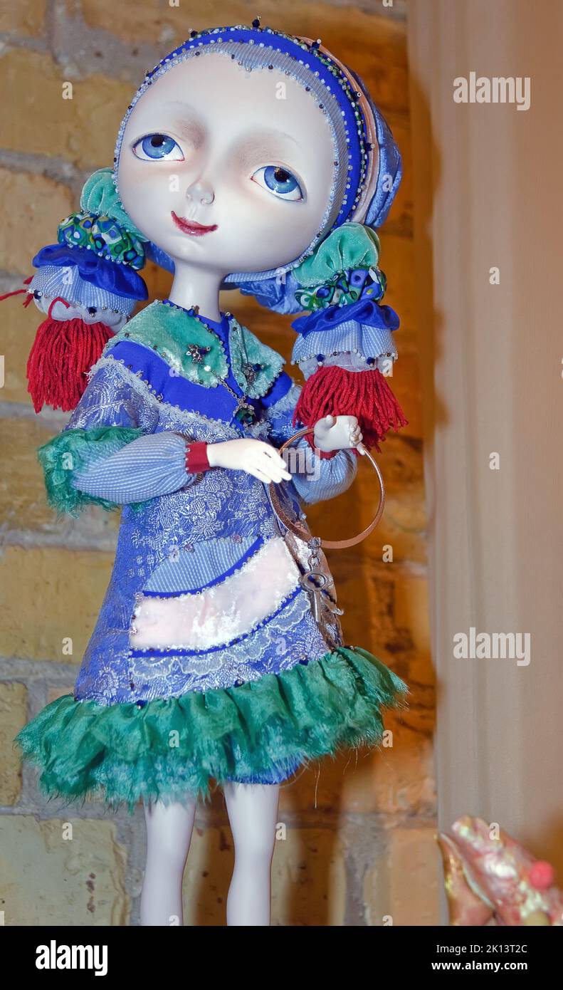 A collectible doll, which resembles a small girl in bright cloth, is on ...