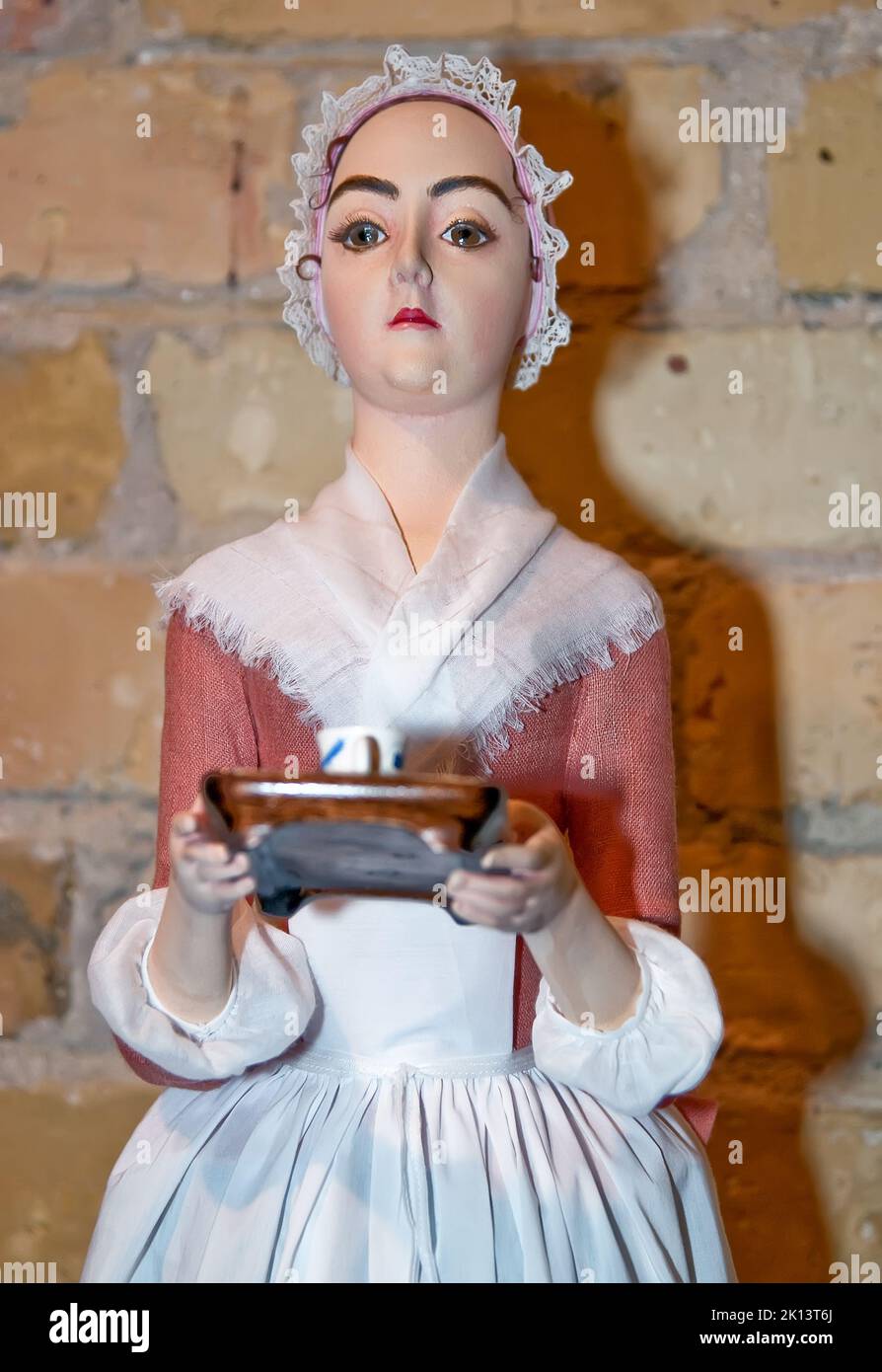 A collectible doll, a servant in white apron and cap detailed, is on ...
