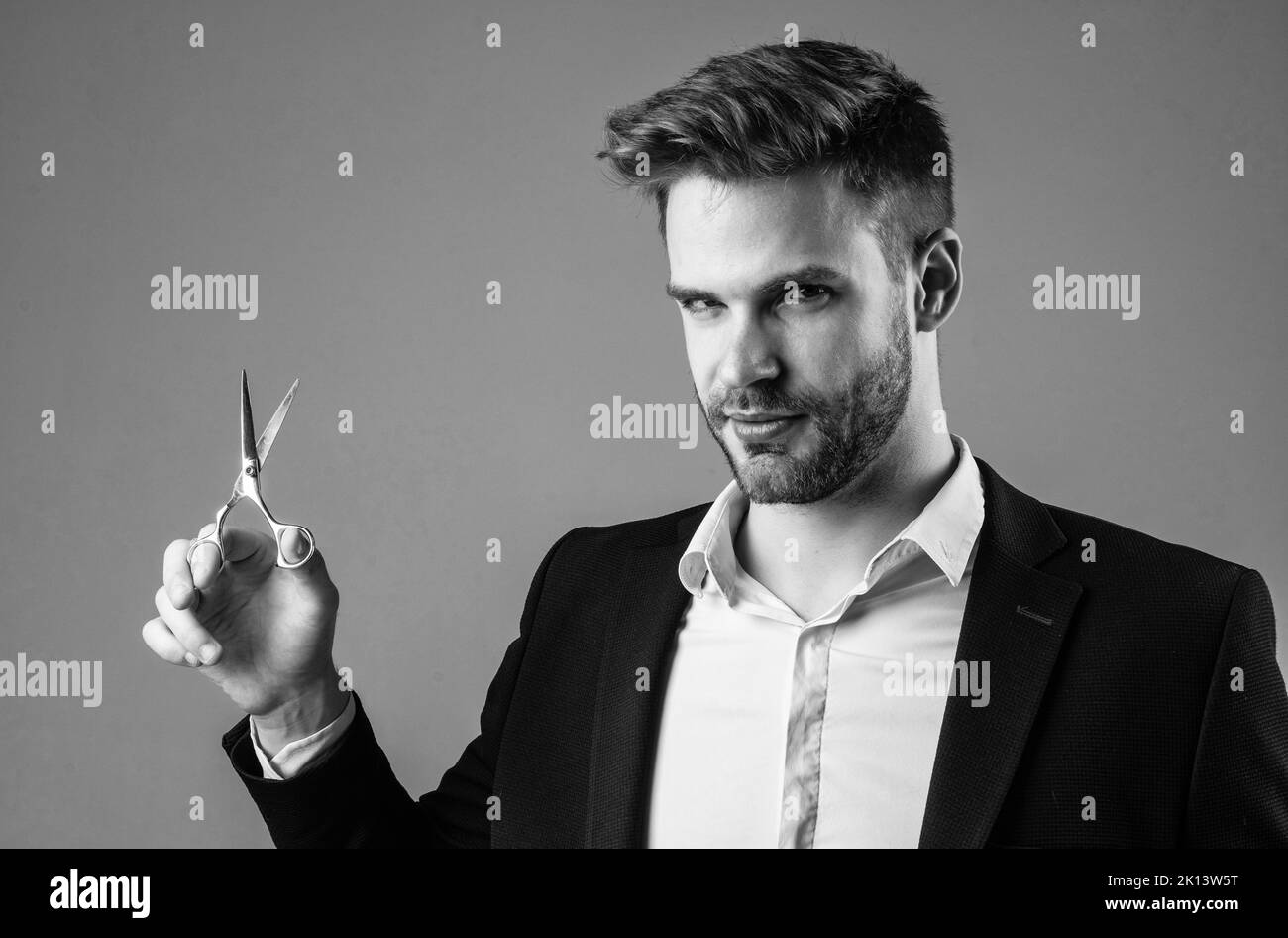 young handsome man in formal wear has bristle on face use scissors ...