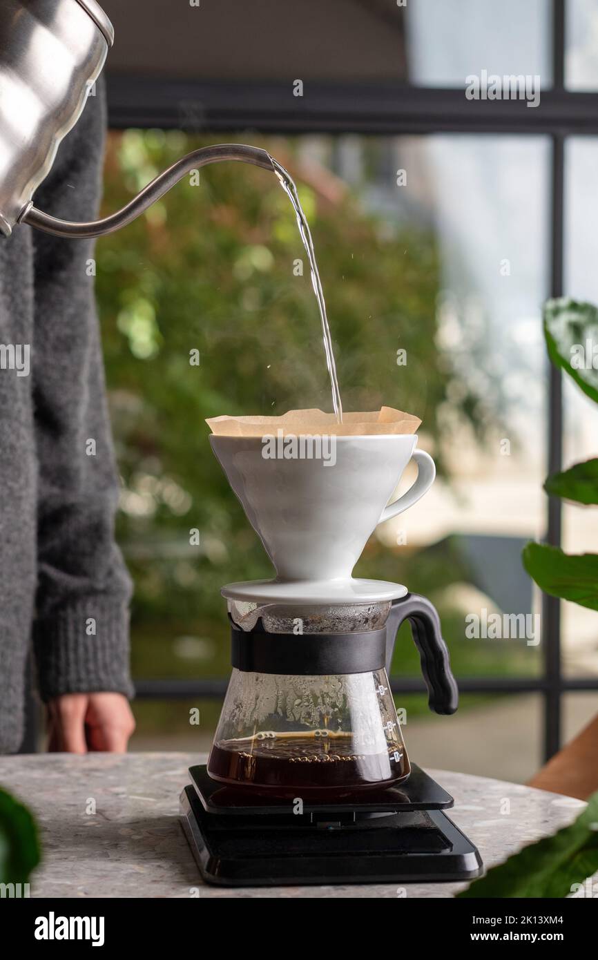 Barista is making drip brewing, filtered coffee, or pour over coffee with hot water and filter ...