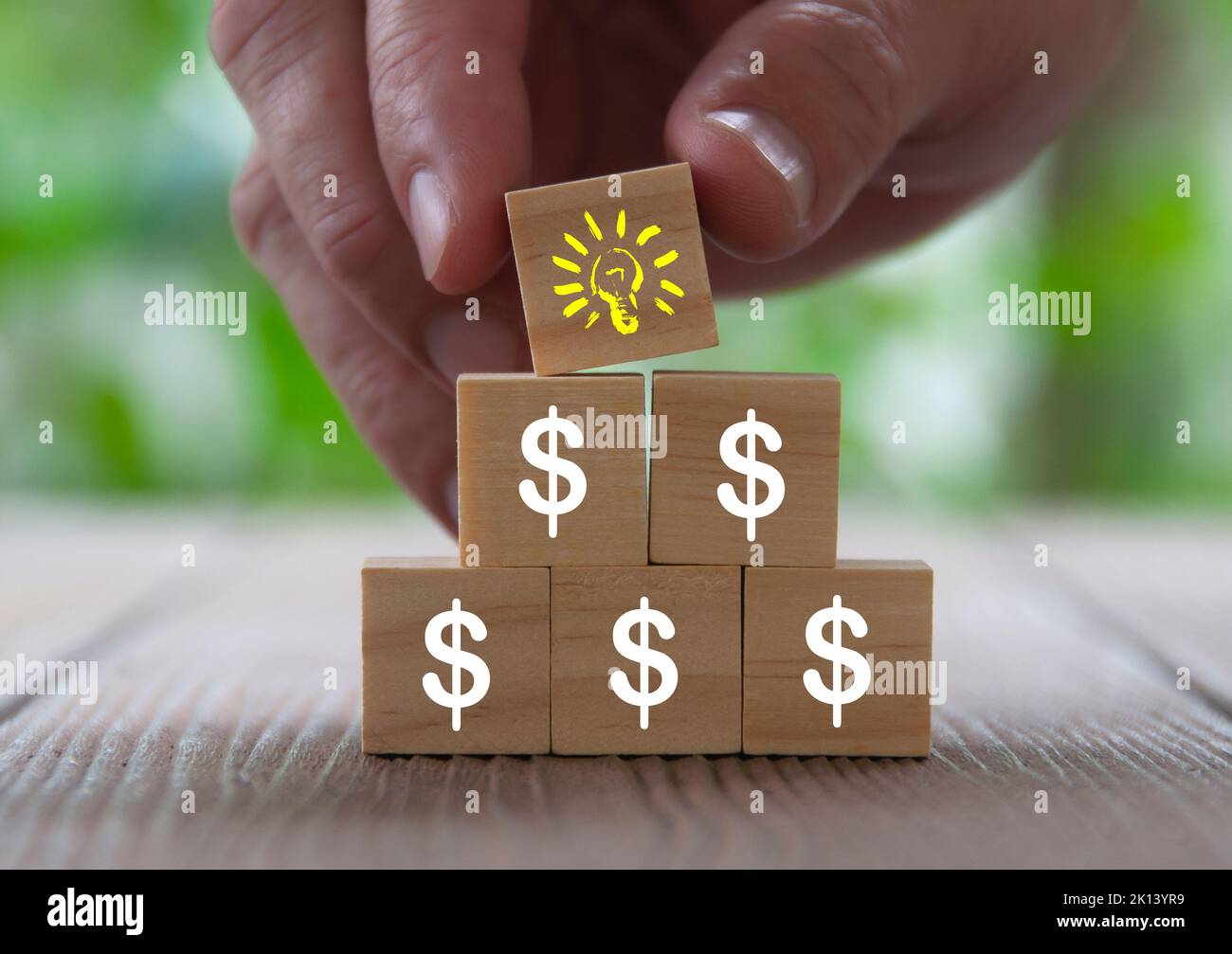 Dollar sign on wooden blocks with hand holding one wooden block with ...