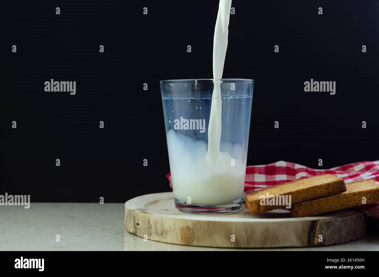 A stream of fresh milk is poured into a glass cup. Natural Product and ...