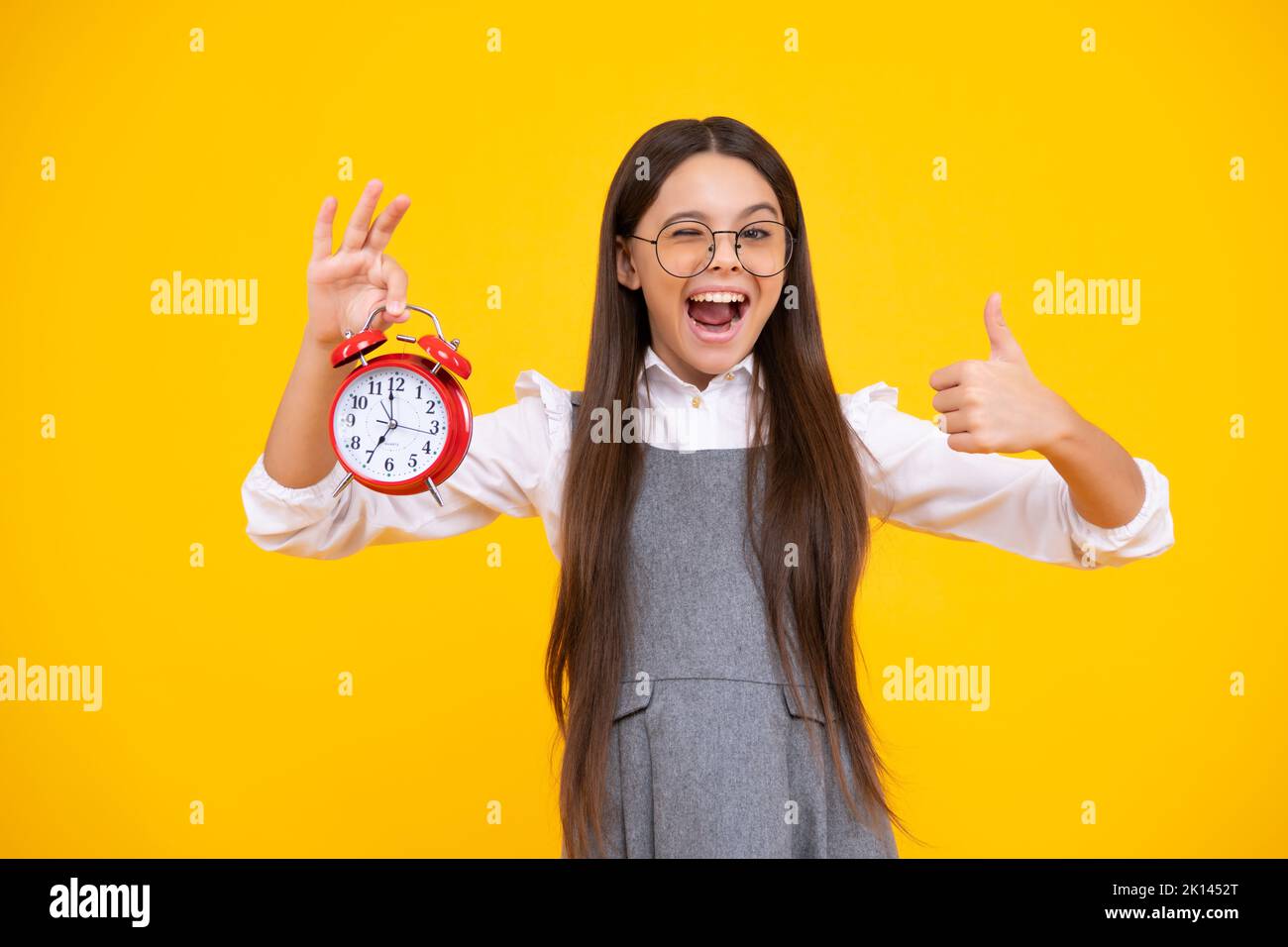Teen student girl hold clock isolated on yellow background. Time to ...