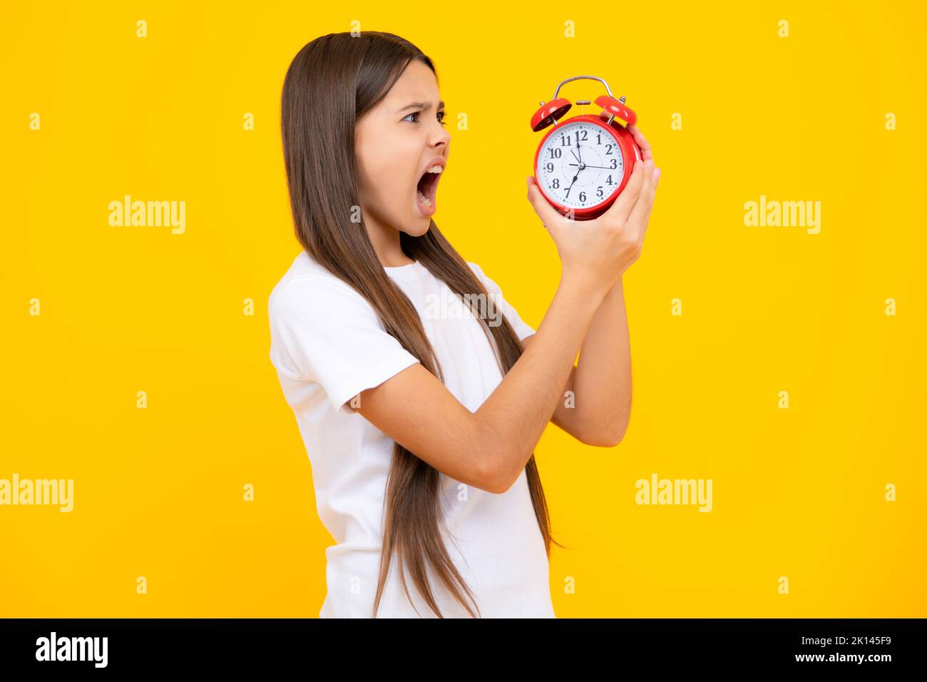 Punctual teen girl checking time. Child with alarm clock showing time ...