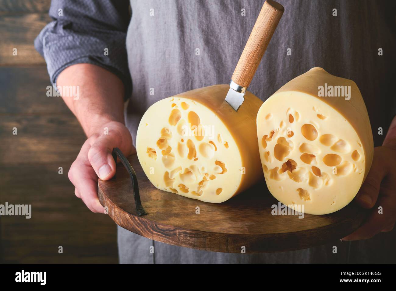 Hands of man hold two big slices of cheese maasdam against background ...
