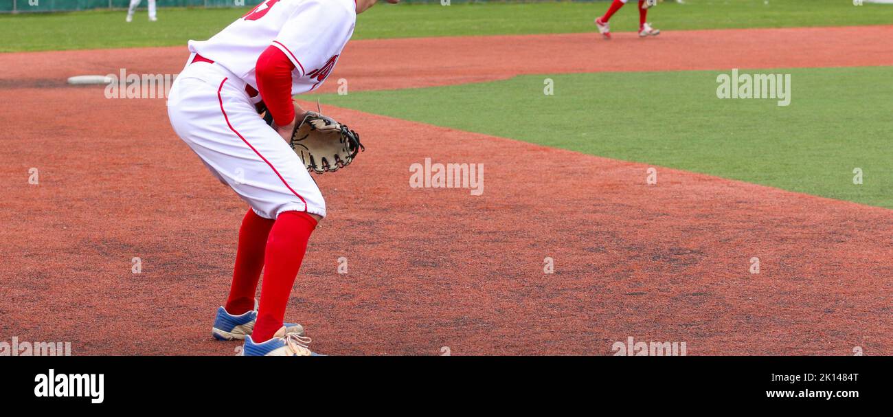 Baseball third baseman ready to field the ball during a game on a red ...