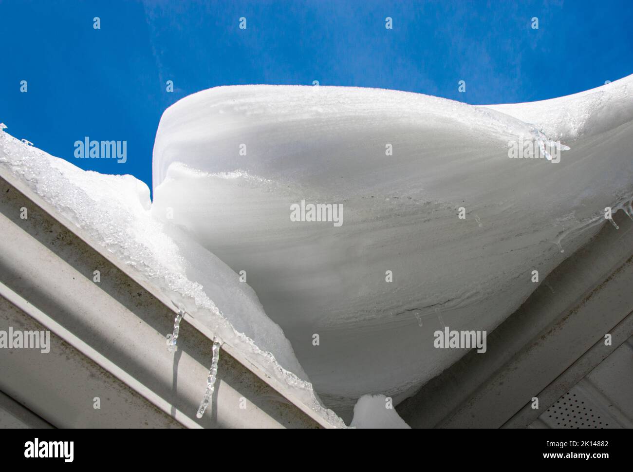 Looking up at snow sliding down a roof a few days after a snow storm ...
