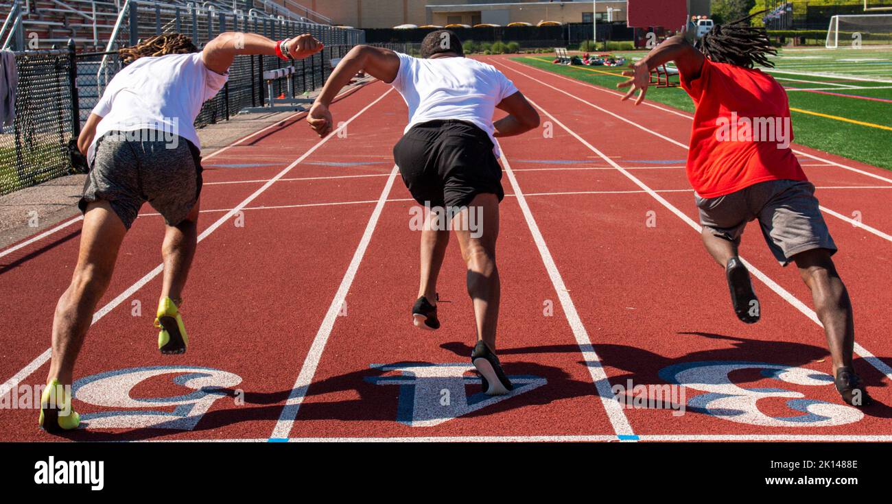 Rear view of three high school boys starting a race from the start ...