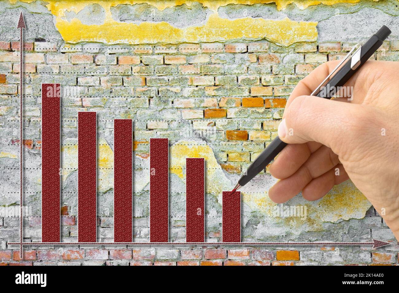 Hand draws a decreasing graph against a brick wall background - concept ...