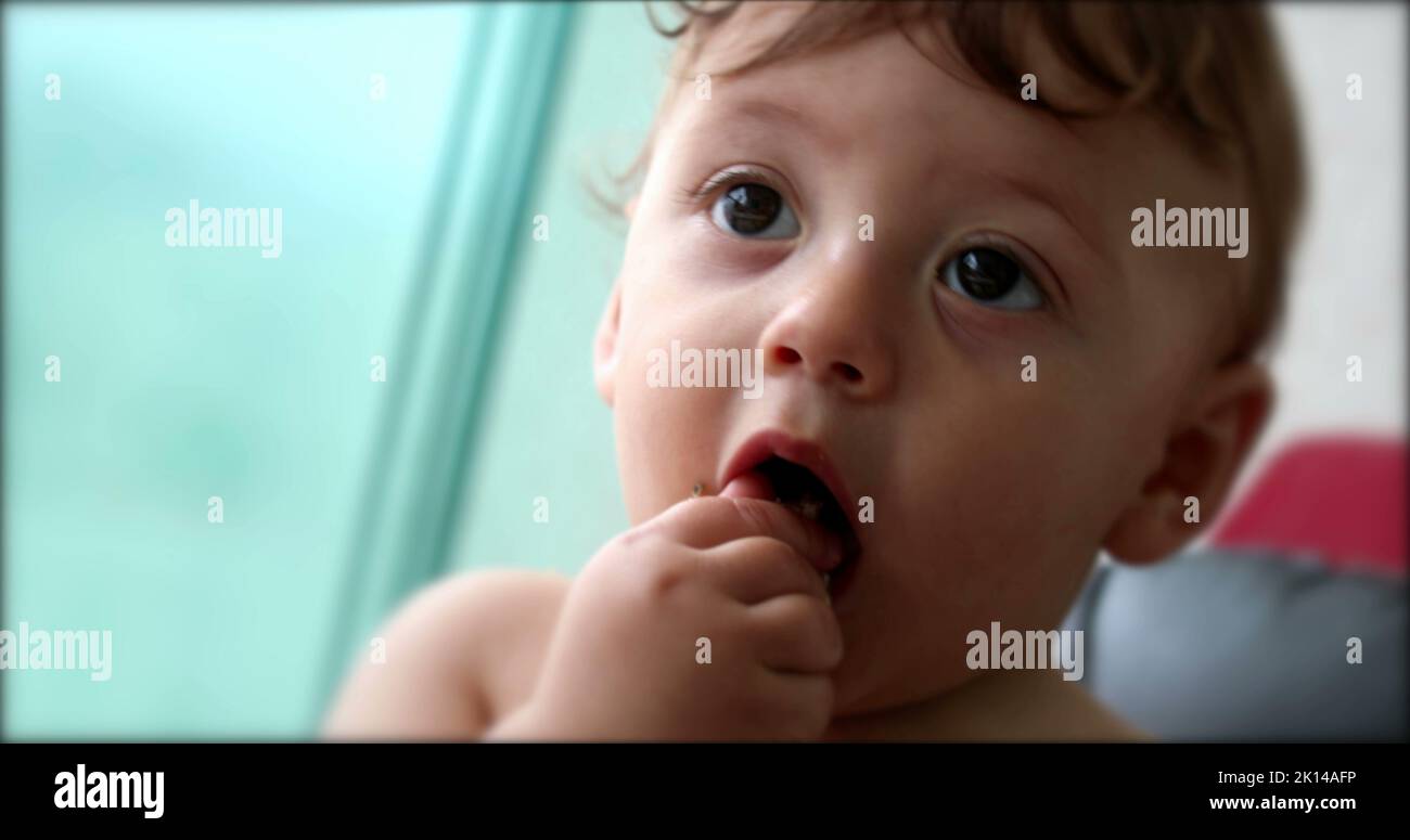 Cute baby portrait eating and spitting food. Close-up infant child face ...