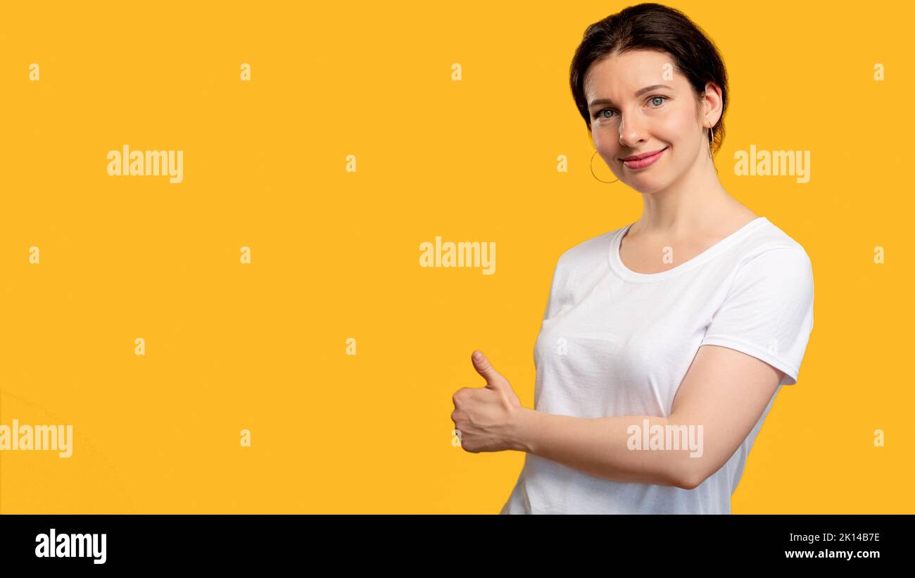 Like gesture. Supporting sign. Happy woman showing thumb up. Looking at ...