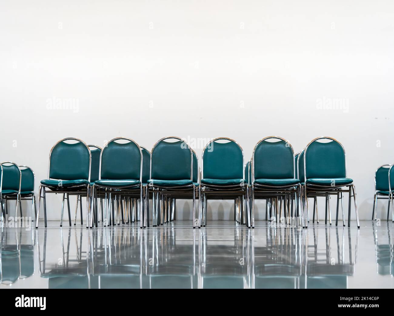 Many empty green leather chairs in a wide hall room, lights on. A floor ...