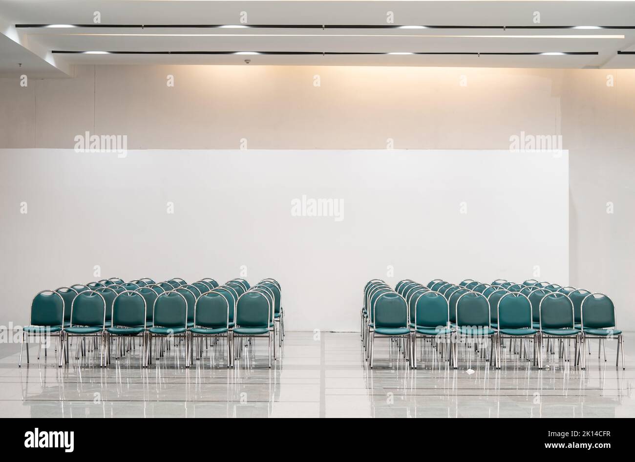 Many empty green leather chairs in a wide hall room, lights on. A floor ...