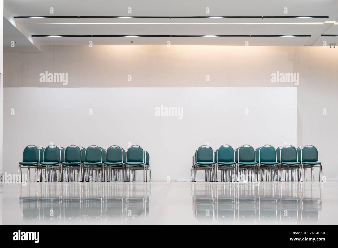 Many empty green leather chairs in a wide hall room, lights on. A floor ...