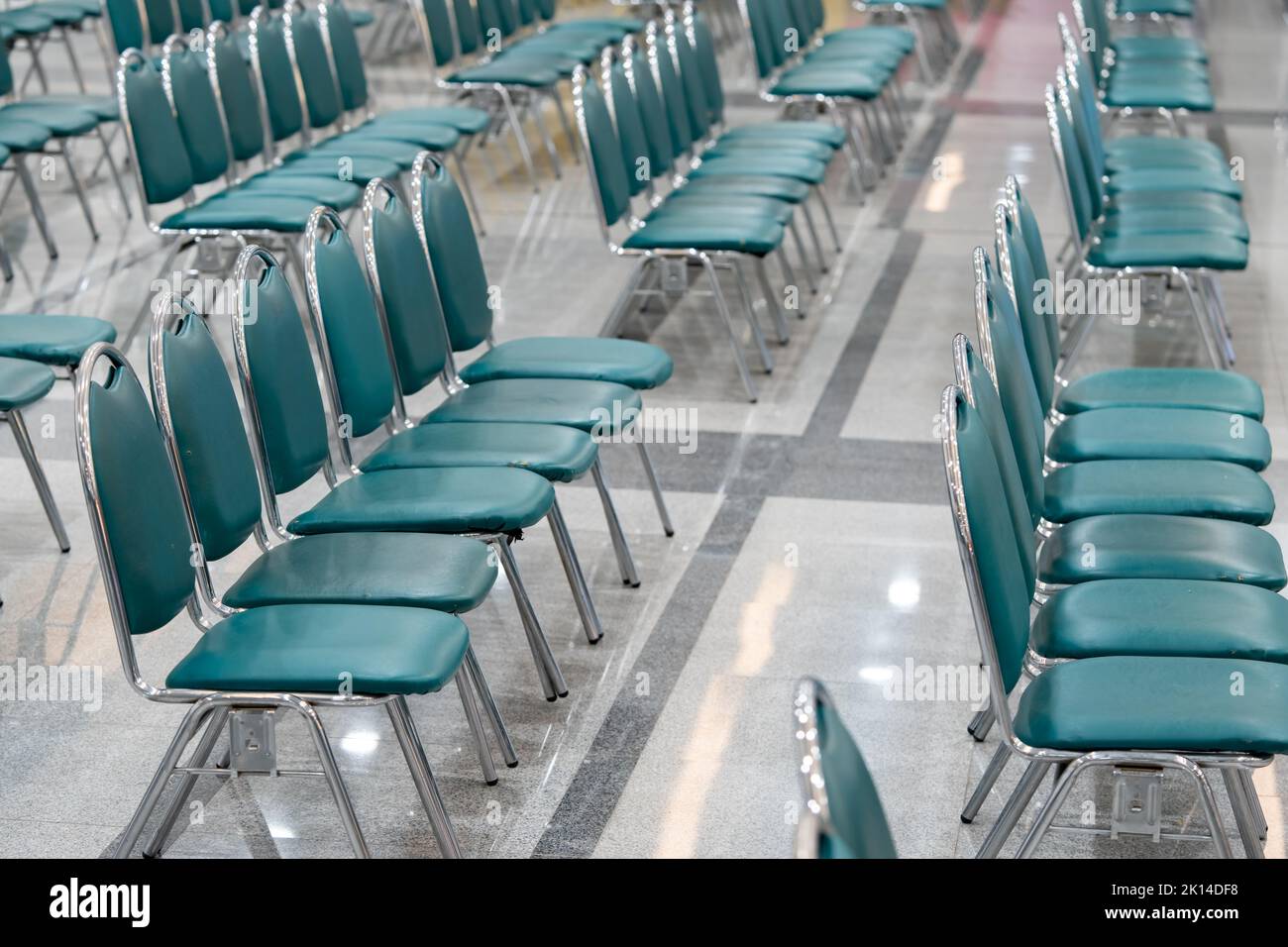 Many empty green leather chairs in a wide hall room, lights on. A floor ...