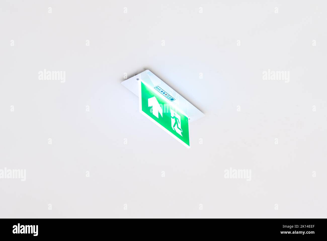 White neon sign depicting a fire exit with green background hangs from ...