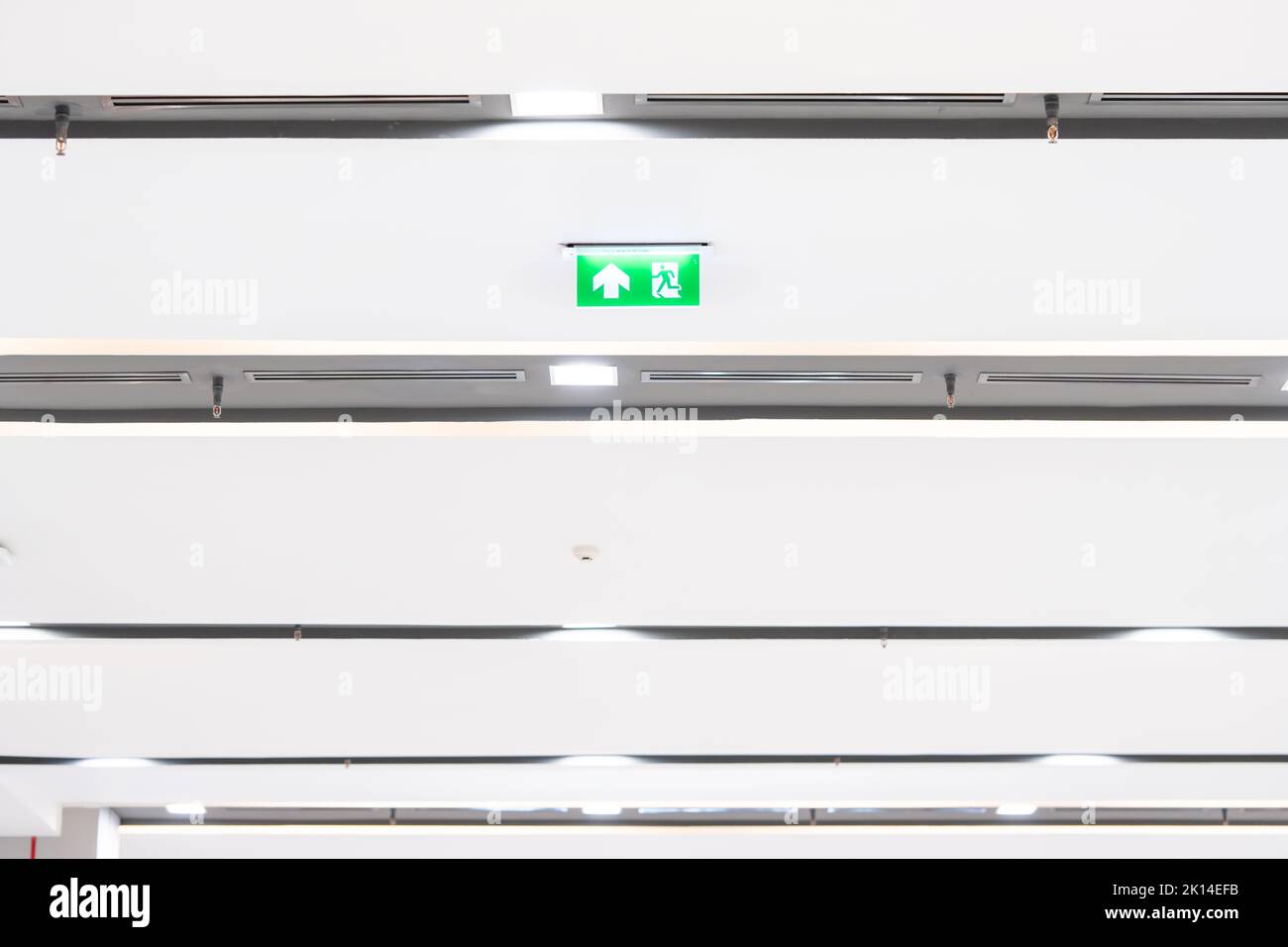 White neon sign depicting a fire exit with green background hangs from ...