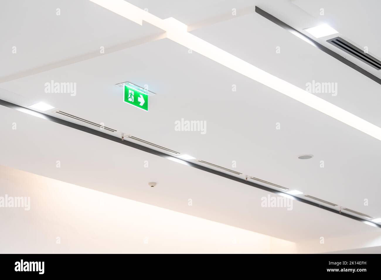 White neon sign depicting a fire exit with green background hangs from ...