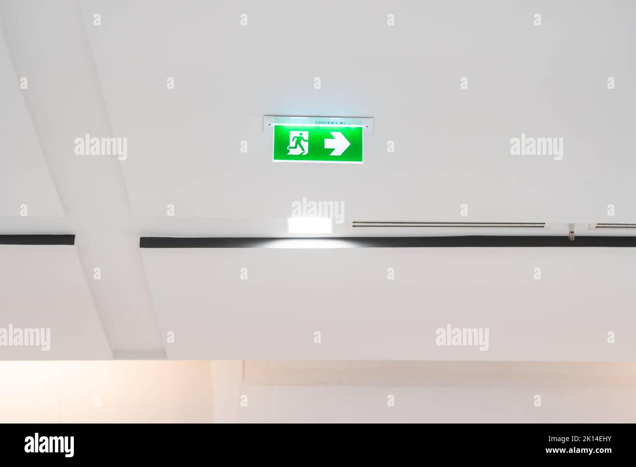 White neon sign depicting a fire exit with green background hangs from ...