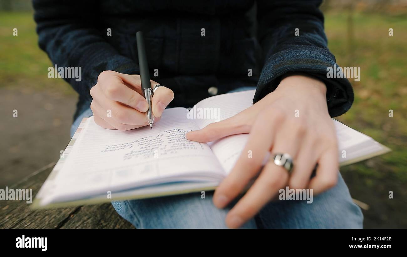 Young creative girl writing down her plans into new notebook or planner ...