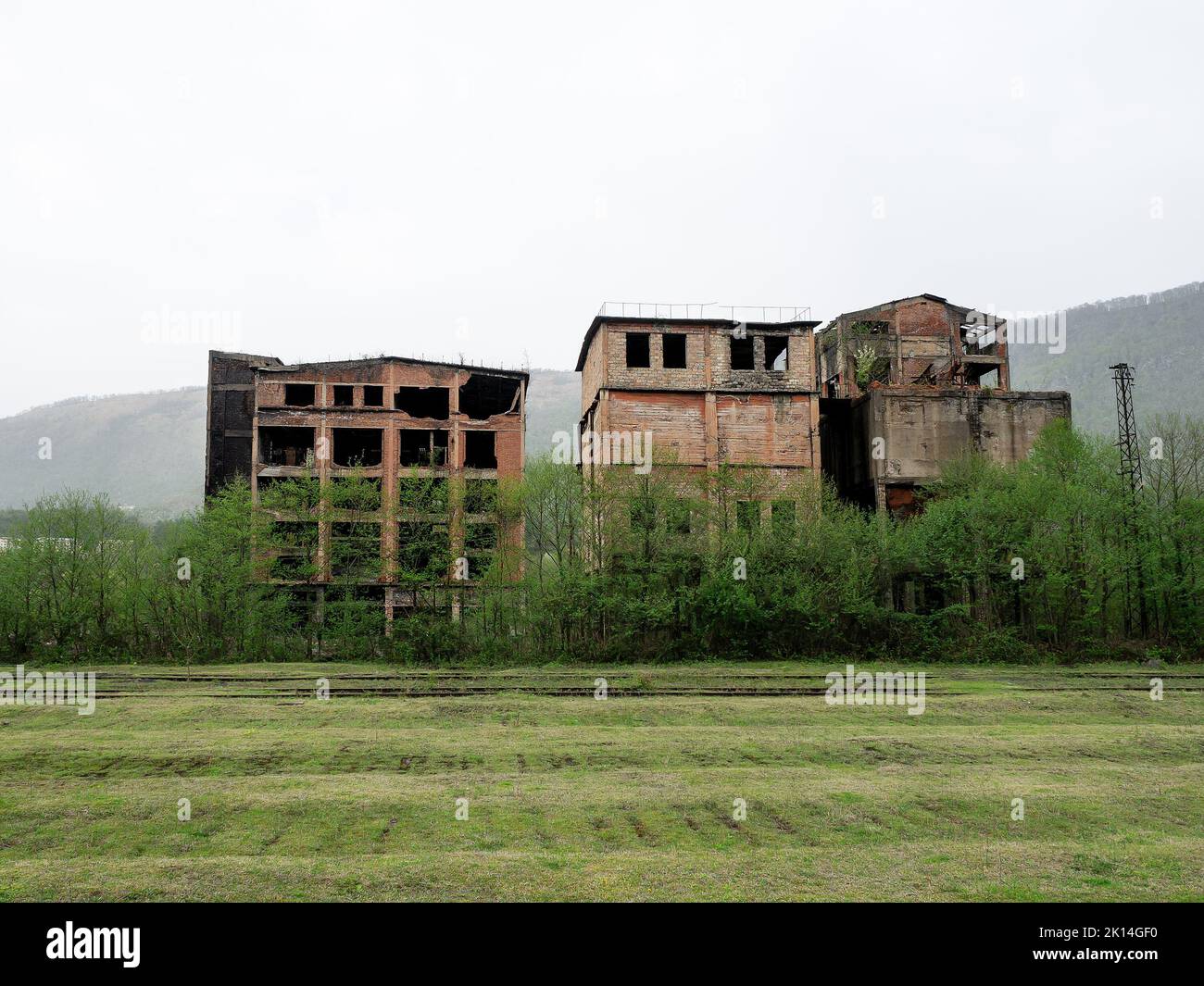 Abandoned brick houses on a green field on a cloudy day Stock Photo - Alamy