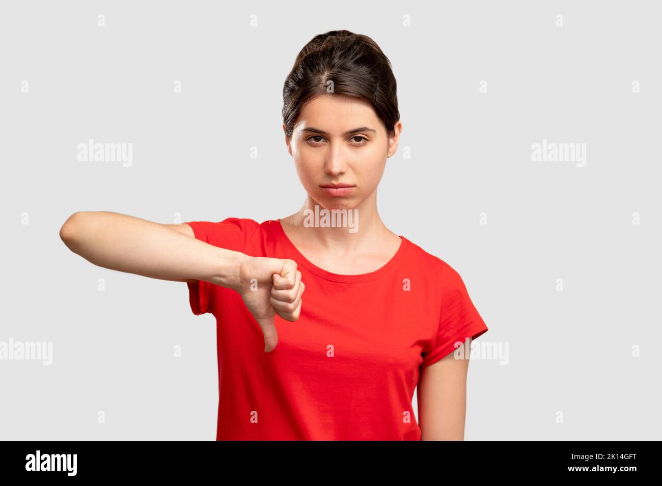 Dislike gesture. Bad job. Sad woman in red t-shirt showing thumb down ...