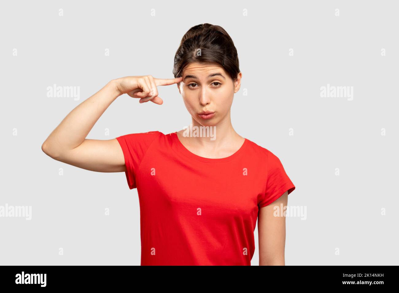 Stupid gesture. Crazy idea. Woman showing cuckoo sign. Looking at ...