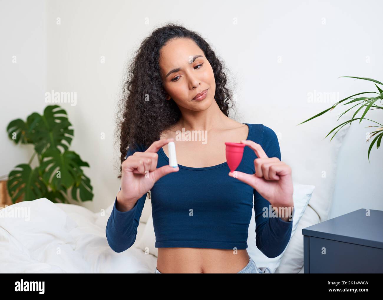 A young multi-ethnic woman holds tampon and menstrual cup for ... A young multi-ethnic woman holds tampon and menstrual cup for ...