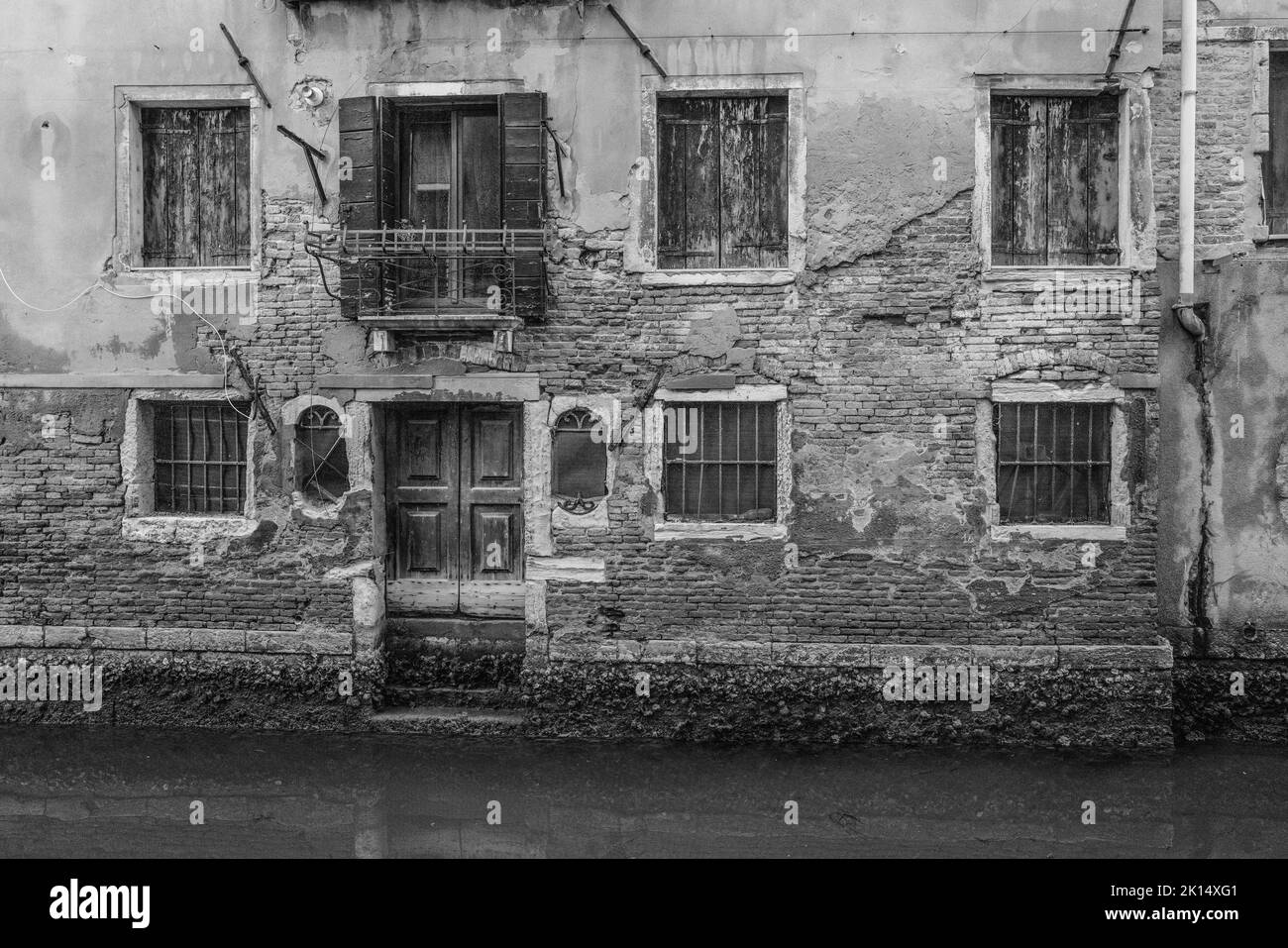Weathered and faded ancient canalside building, Venice, Italy. Black ...