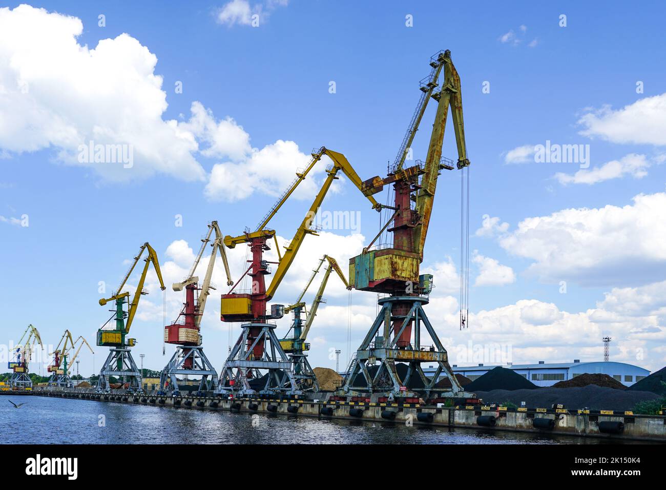 Bulk cargo terminal in port with many shore cranes and piles of coal ...