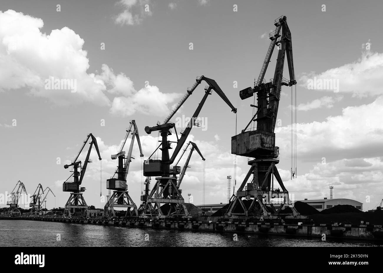 Bulk cargo terminal in port with many shore cranes and piles of coal ...