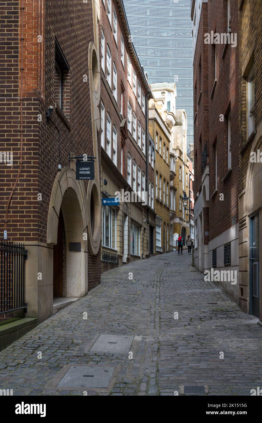 Young man and woman walk uphill along Lovat Lane, a narrow cobbled ...