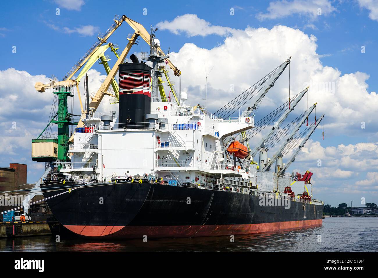 Large bulk carrier with open holds in harbor cargo terminal, shore ...