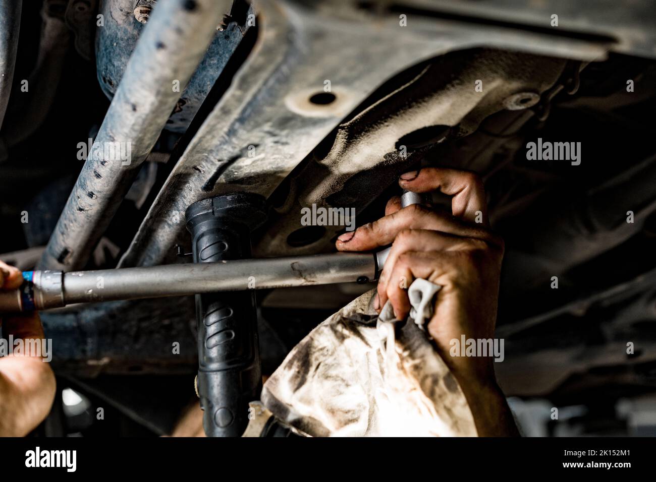 Mechanic repairing under car at the car service garage Stock Photo - Alamy