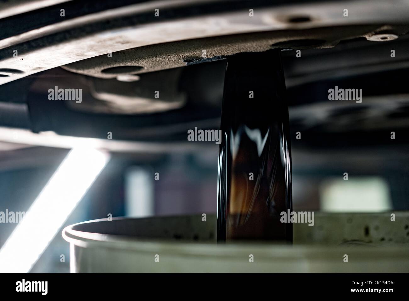 Old dirty oil pouring from the car engine in car service station close ...